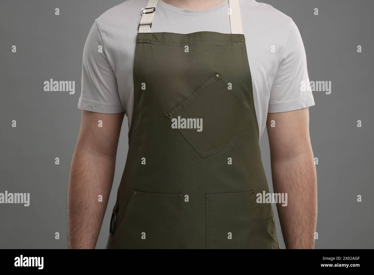 Man in kitchen apron on grey background, closeup. Mockup for design ...