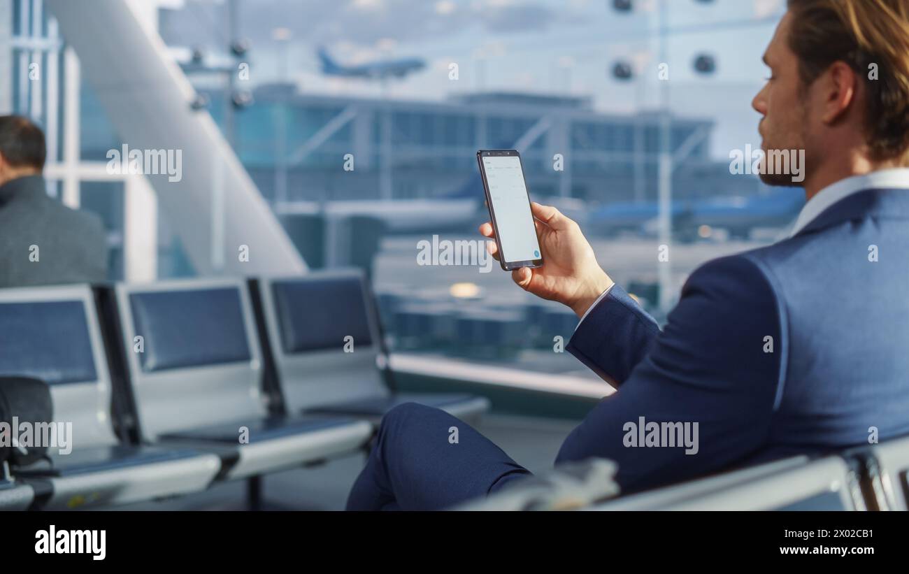 Airport Terminal: Businessman is Setting an Alarm Clock on Mobile ...