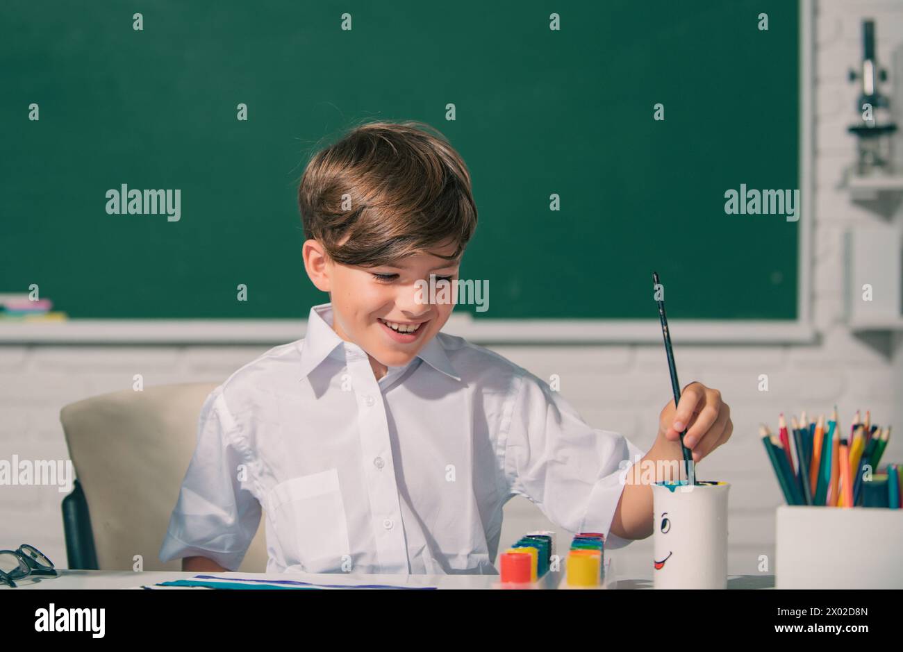 Child boy drawing cute draw using colored pencils at school or ...