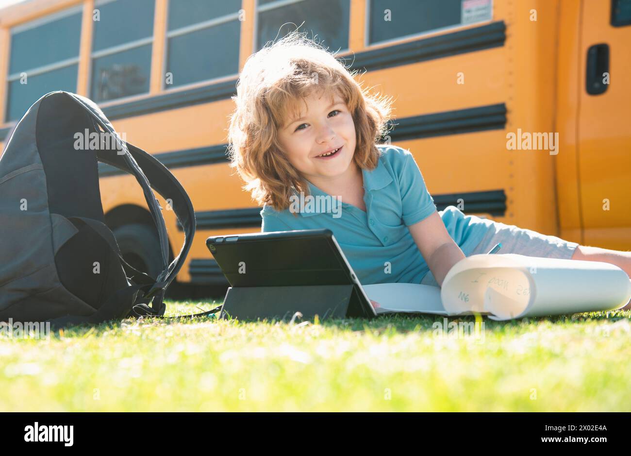 Portrait of smart schoolboy writing outdoor in school park and doing ...