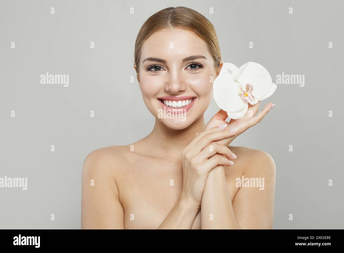 Smiling young woman with fresh silky skin posing on white background ...