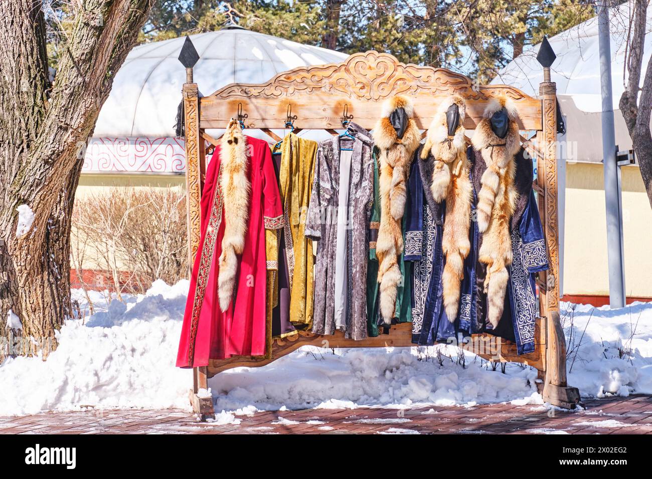 Carved wooden hanger with Kazakh festive colorful clothes for a tourist ...