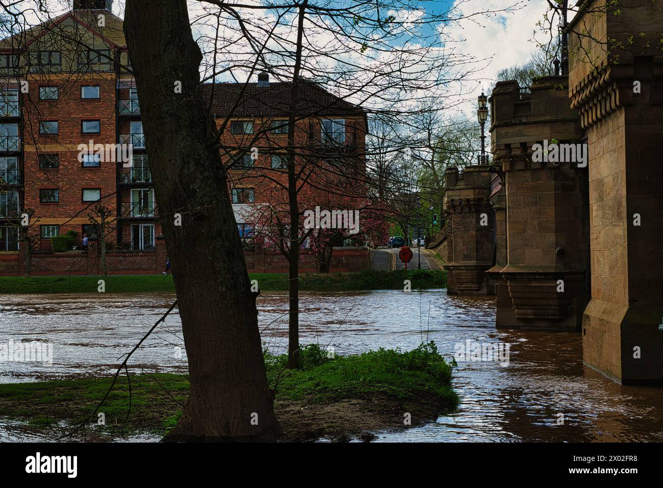 Urban riverside scene with swollen river waters, lush greenery, and a ...