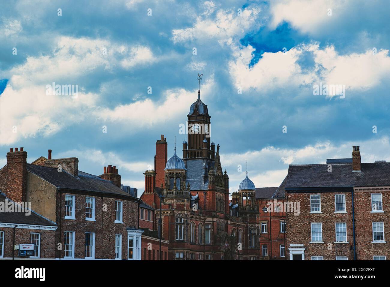 Dramatic clouds loom over a historic town center, featuring a prominent ...