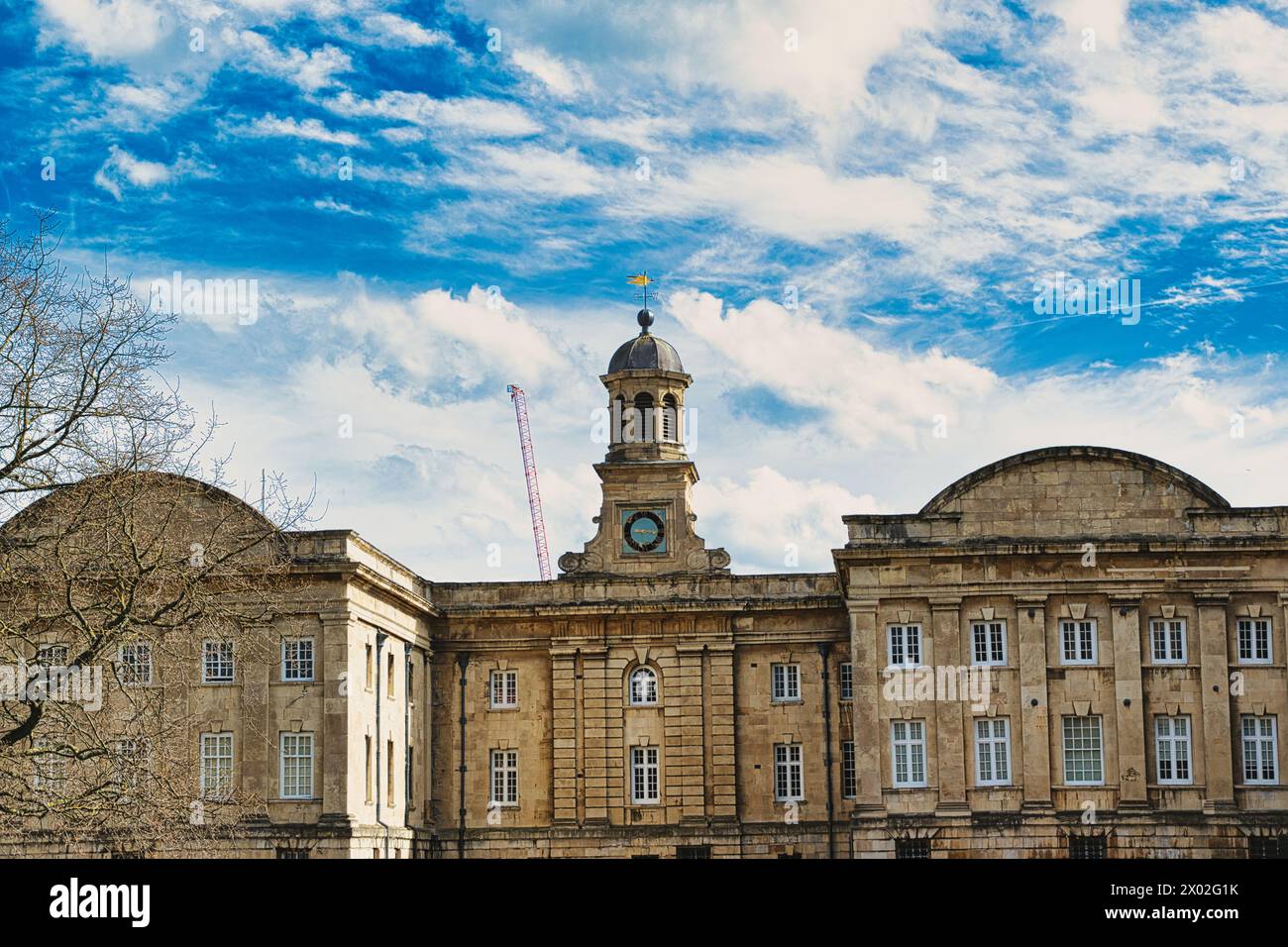 Historic stone building with a central clock tower under a blue sky ...