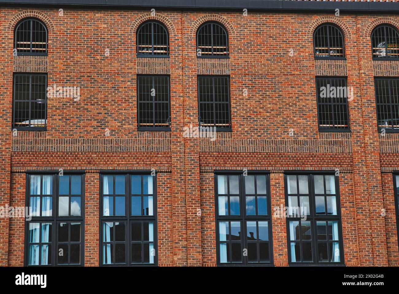 Facade of a vintage brick building with rows of windows reflecting the ...