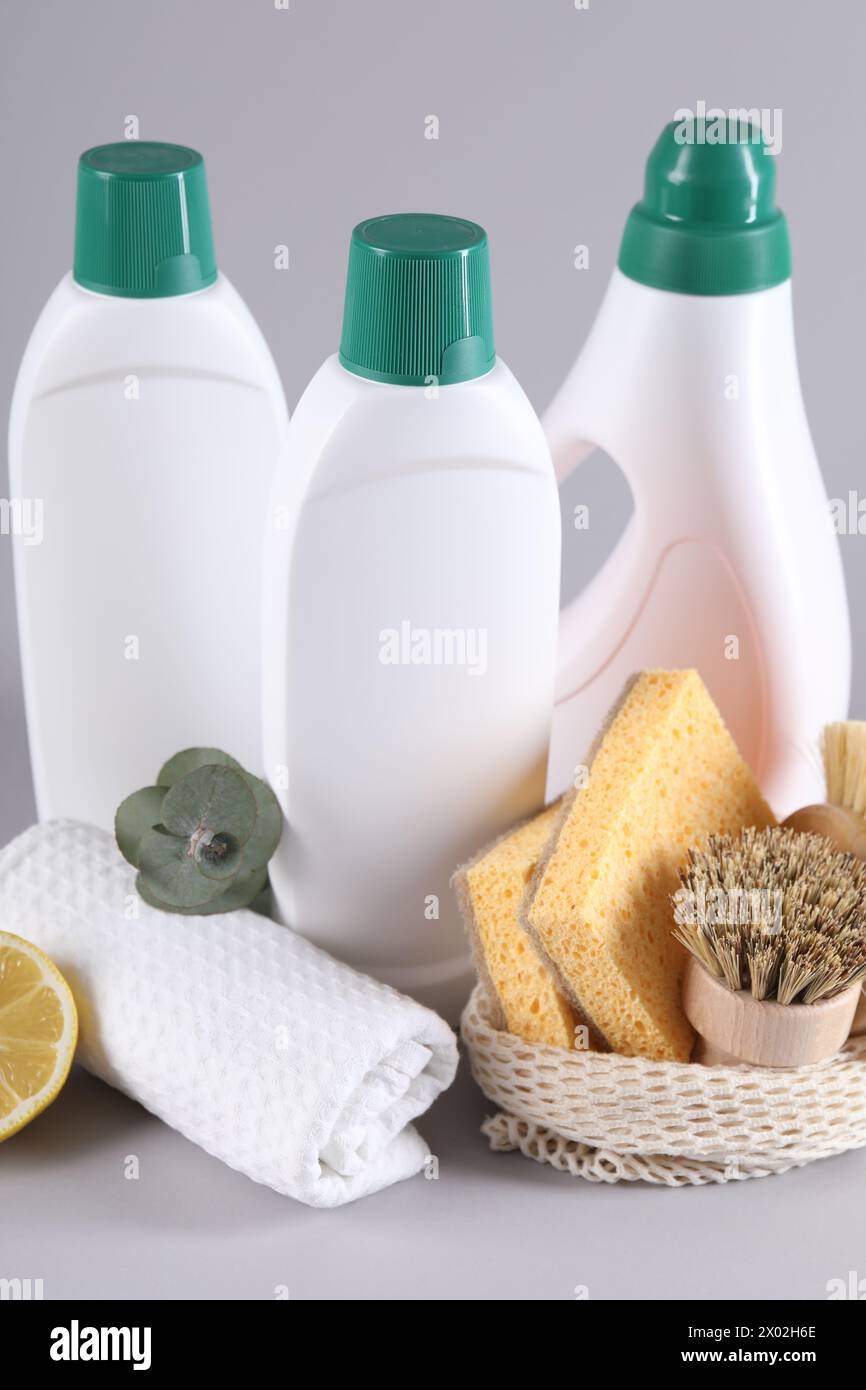 Bottles of cleaning product, sponges, brushes, lemon and rag on light ...