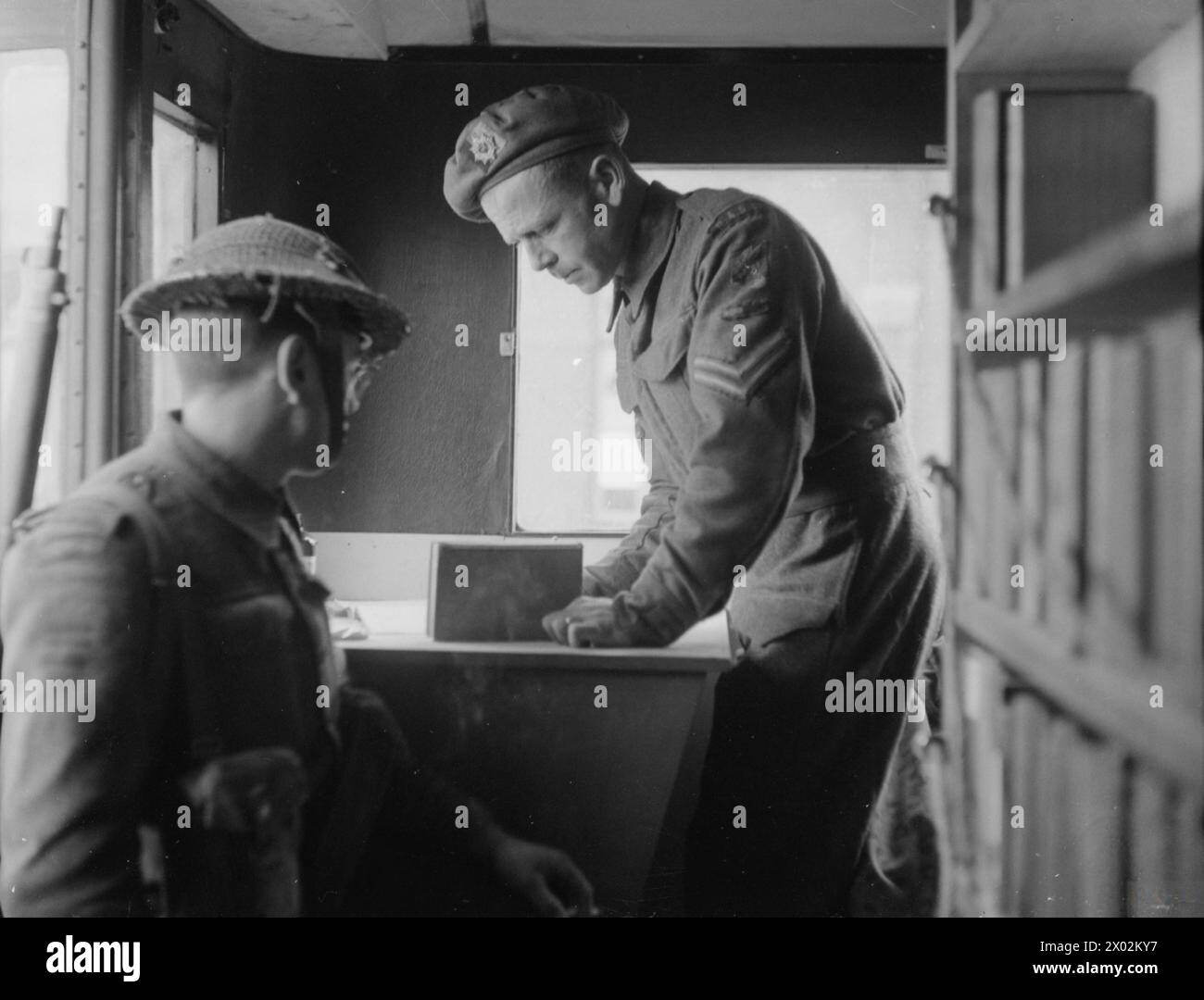 Corporal E. Seyd, librarian, checks out a book to Private Edward Delf ...