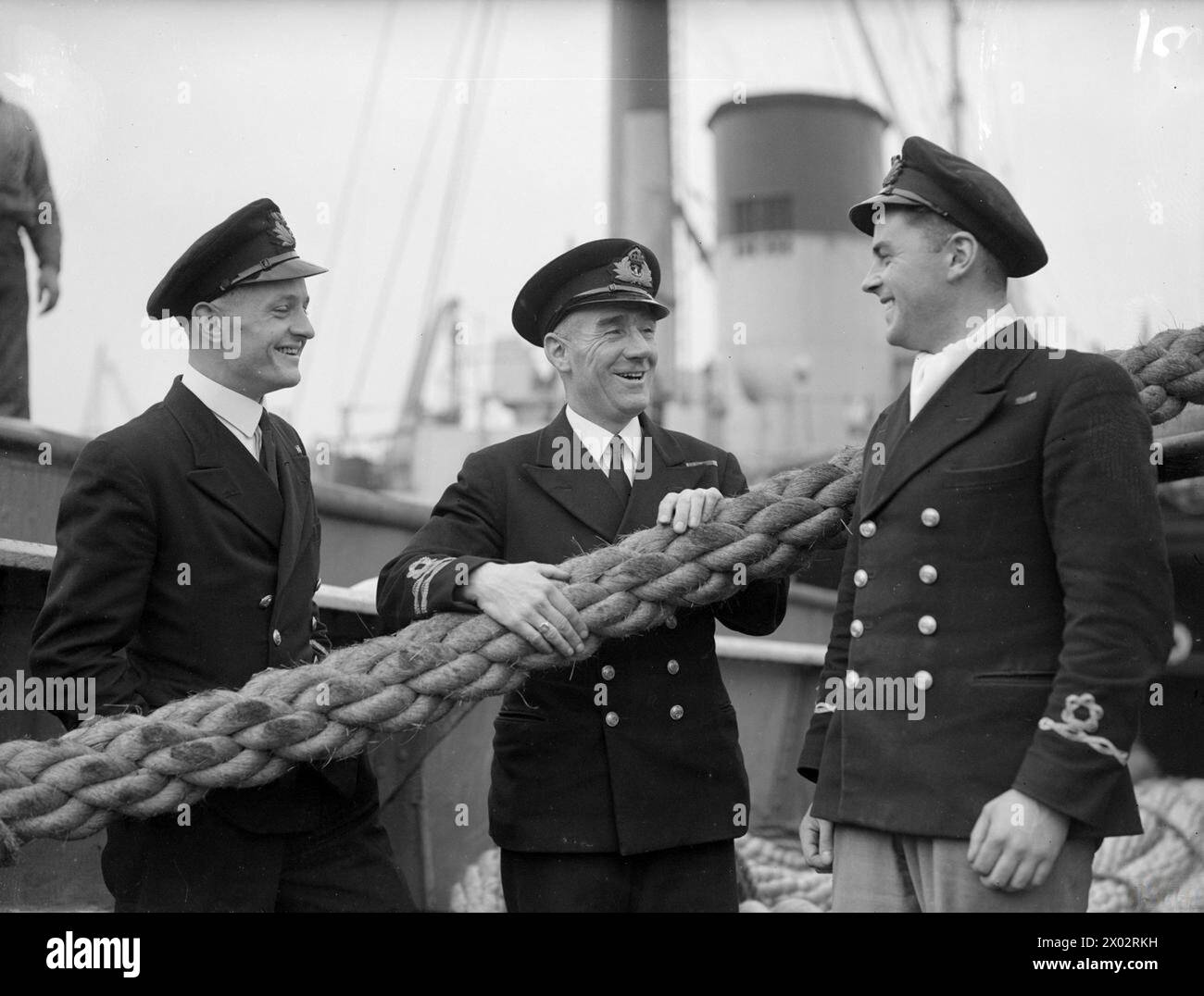 Officers of HMS Saucy, a Royal Navy rescue tug, stand beside tow ropes ...