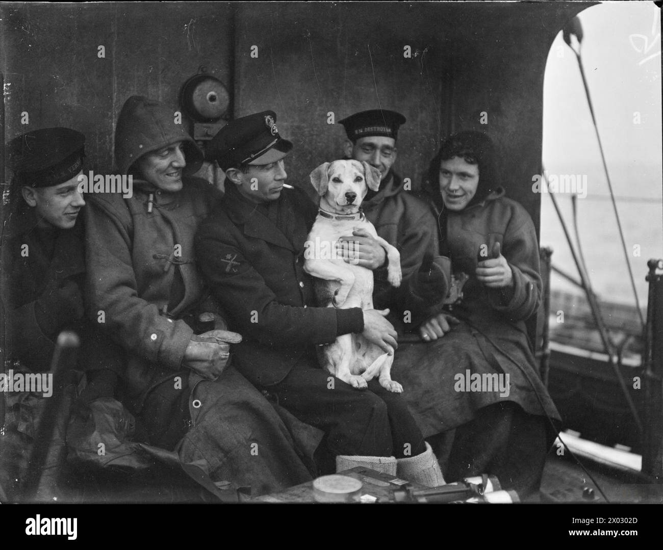 Pluto, the dog mascot of HMS Cossack, sits on a crew member's lap while ...