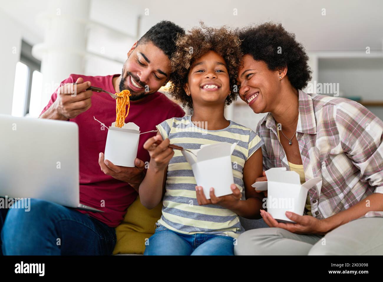 Happy african family eating at living room and enjoying time together ...