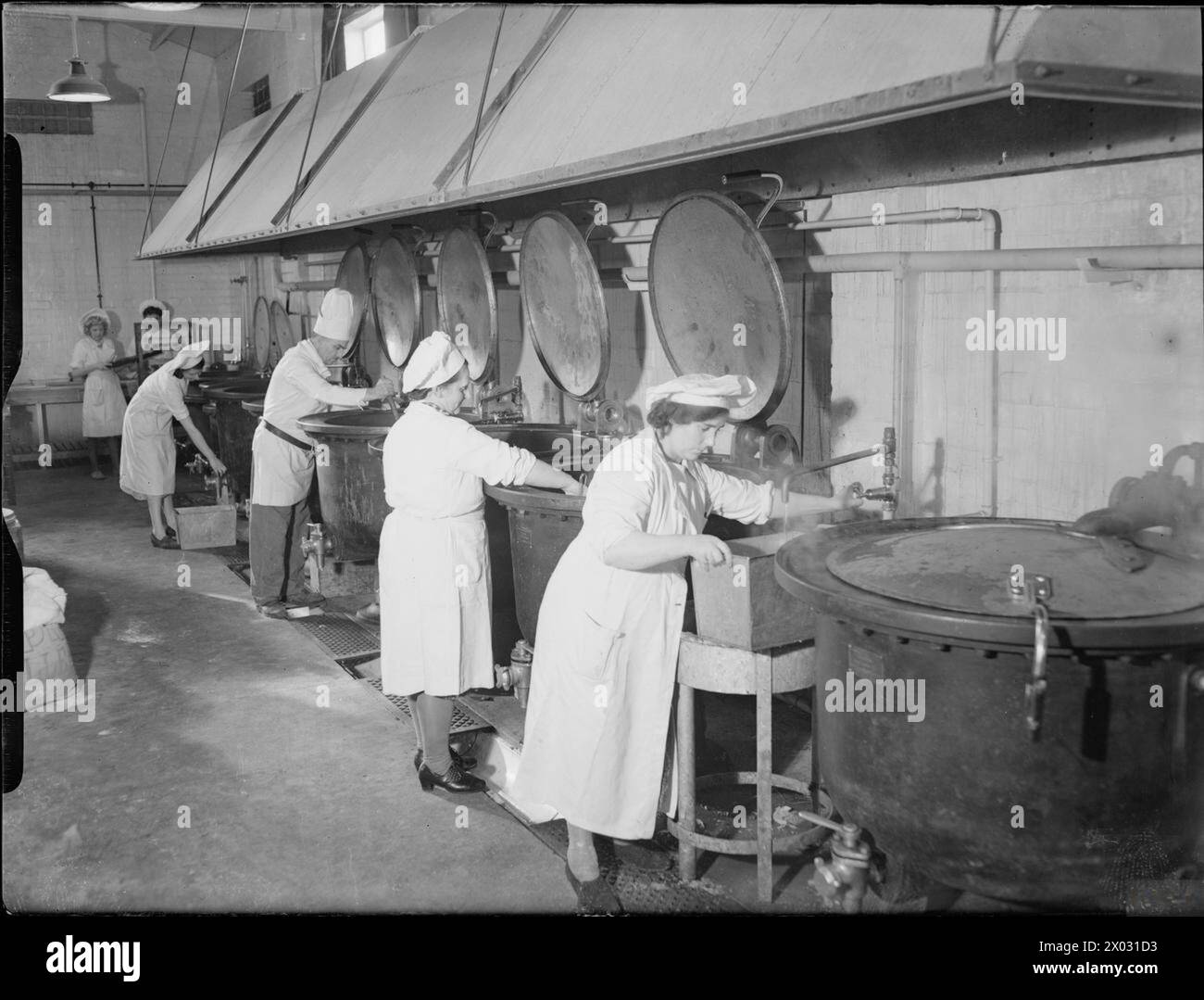FACTORY CANTEEN KITCHENS, UK, 1942 - Cooks work at a row of large ...