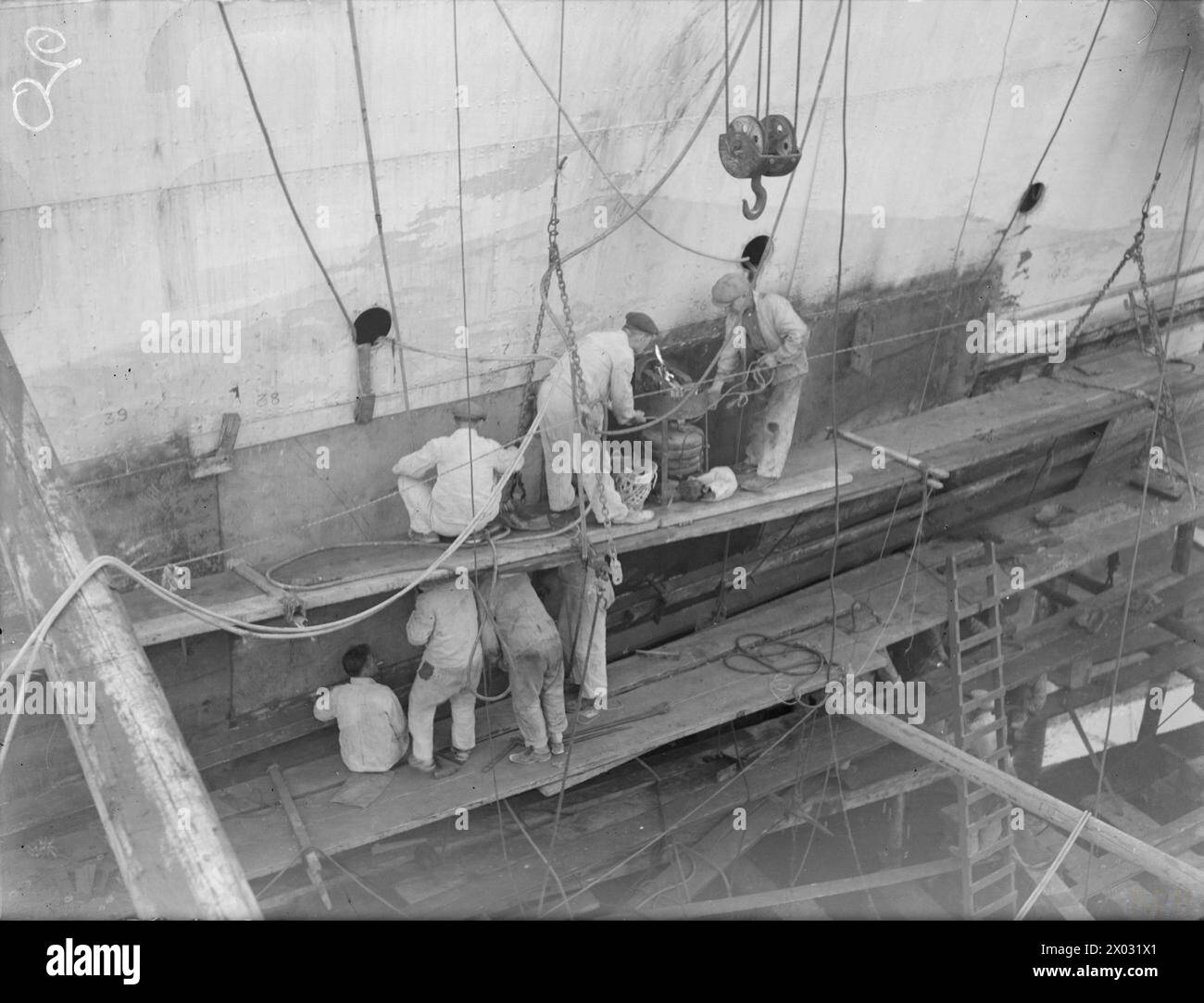 Dockyard workers repair the starboard side of HMS Matchless in dry dock ...