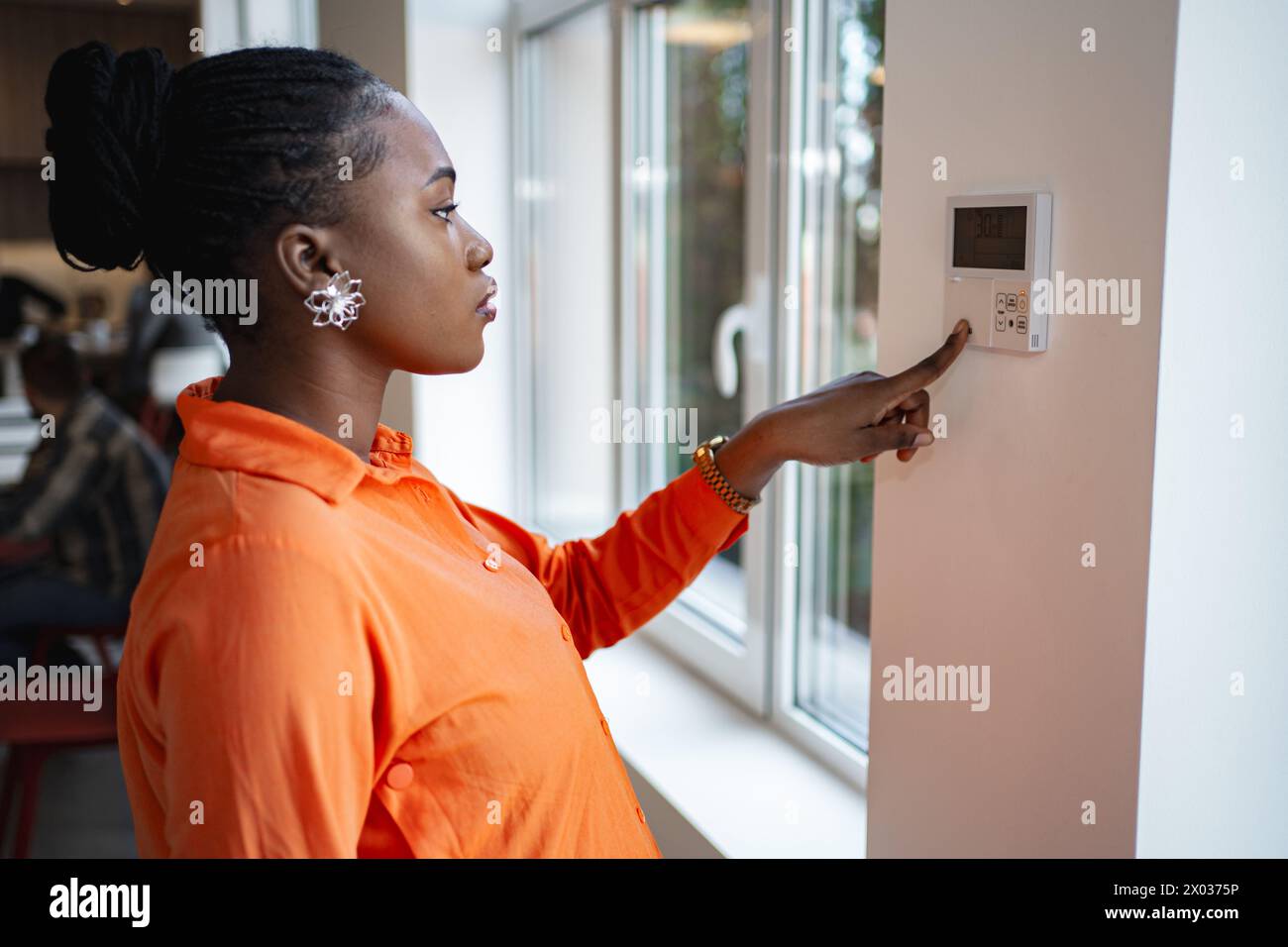 Woman in Orange Shirt Pressing Buttons on Wall Stock Photo - Alamy