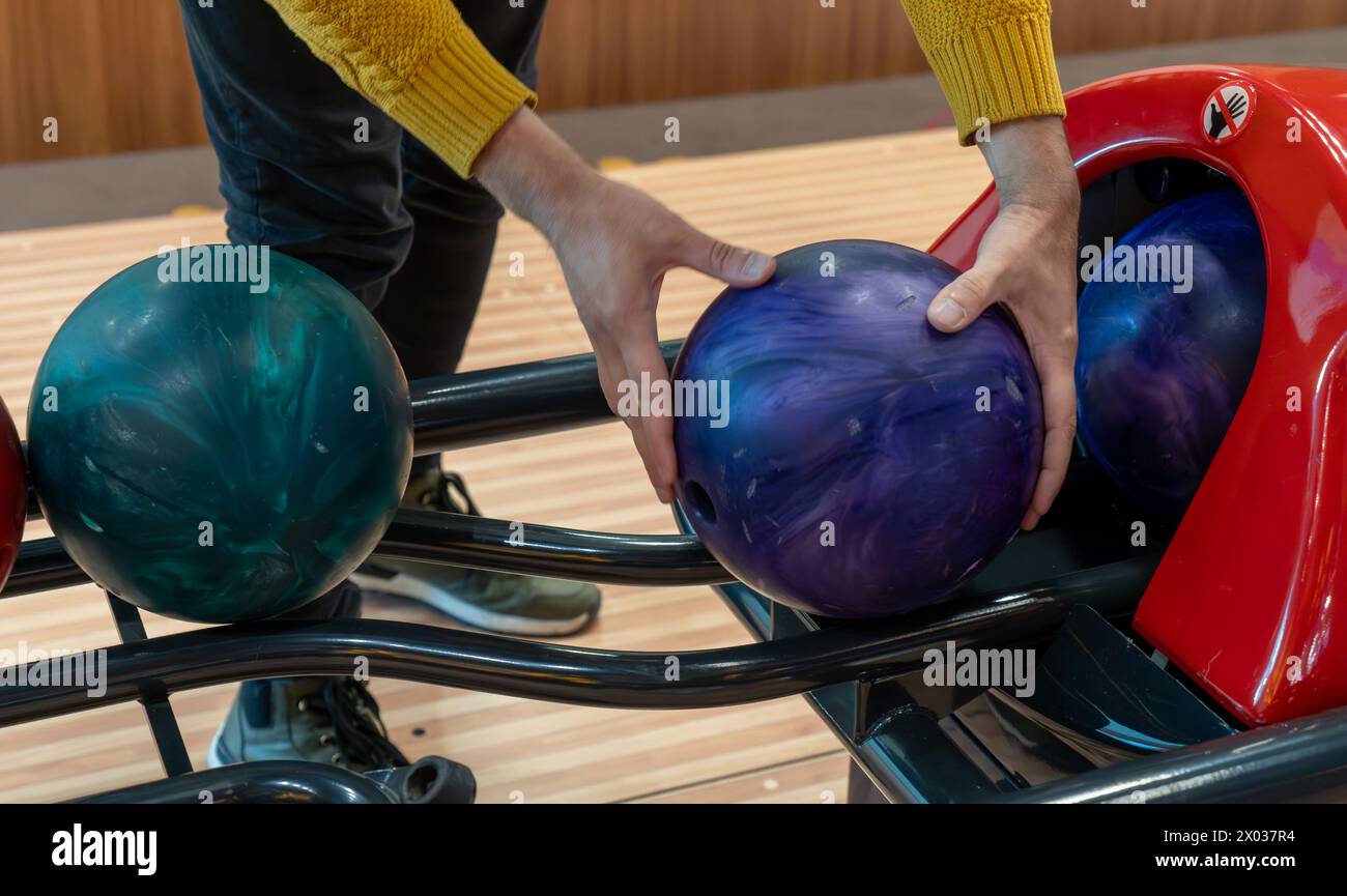 Person selecting colorful bowling balls from the rack at a bowling ...