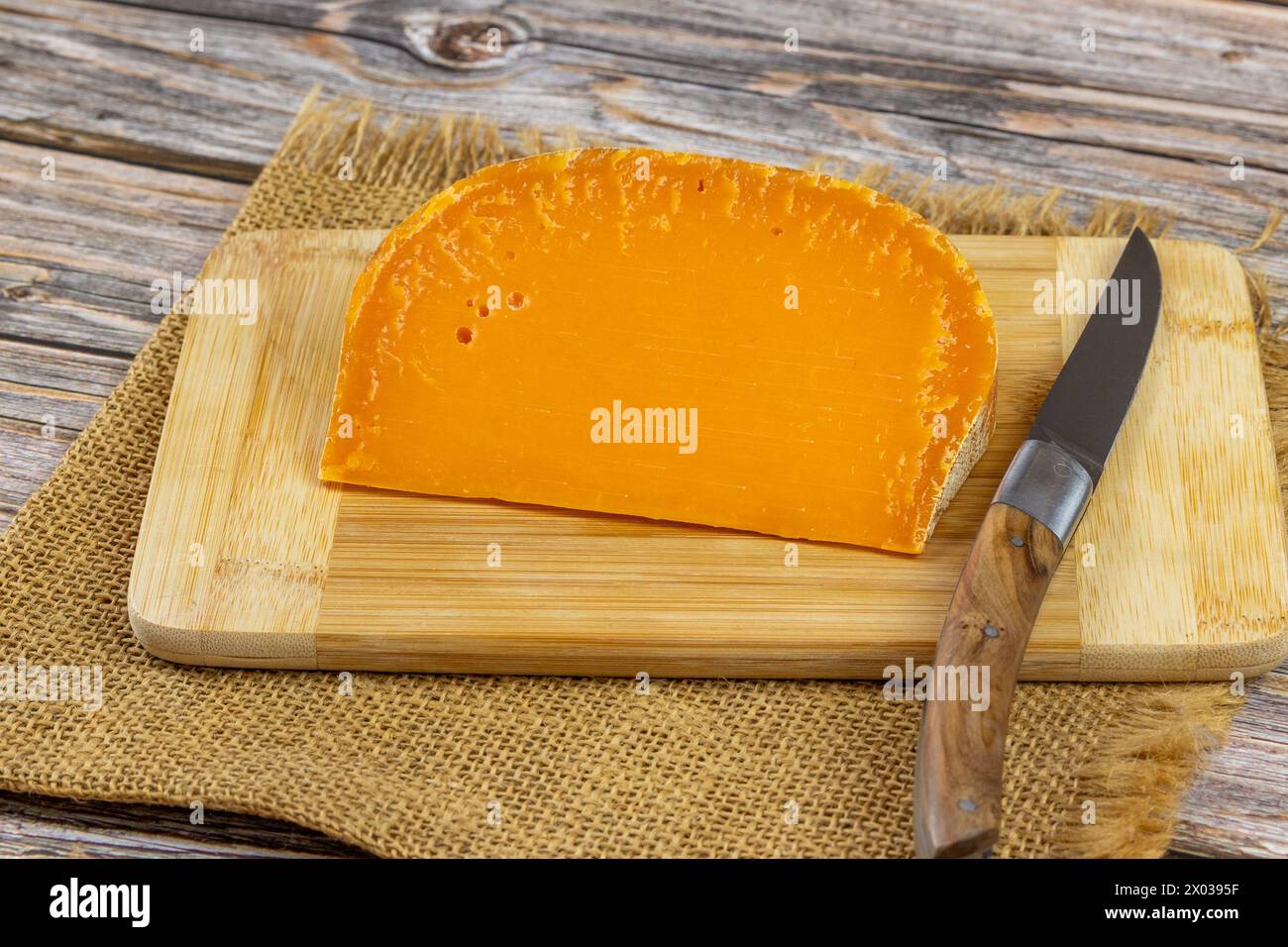 slice of French cheese: extra old mimolette, close-up, on a cutting ...