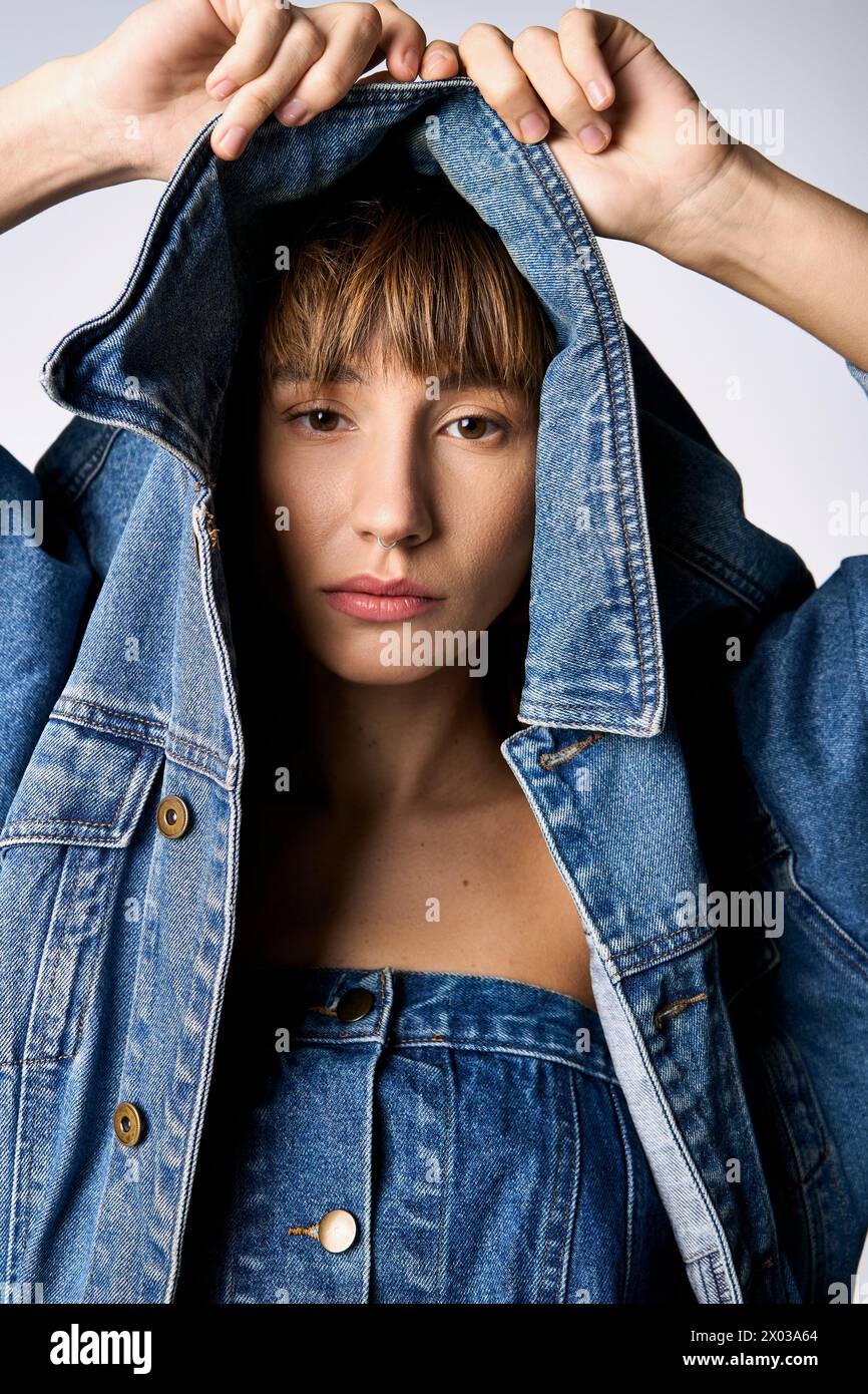 A young woman with short hair joyfully raises her jean jacket over her ...