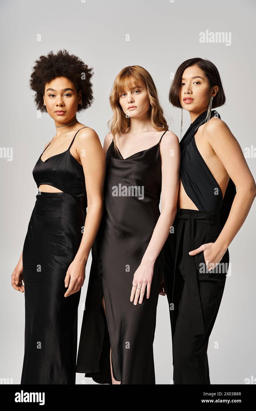 Three women of different ethnicities standing together in black dresses ...