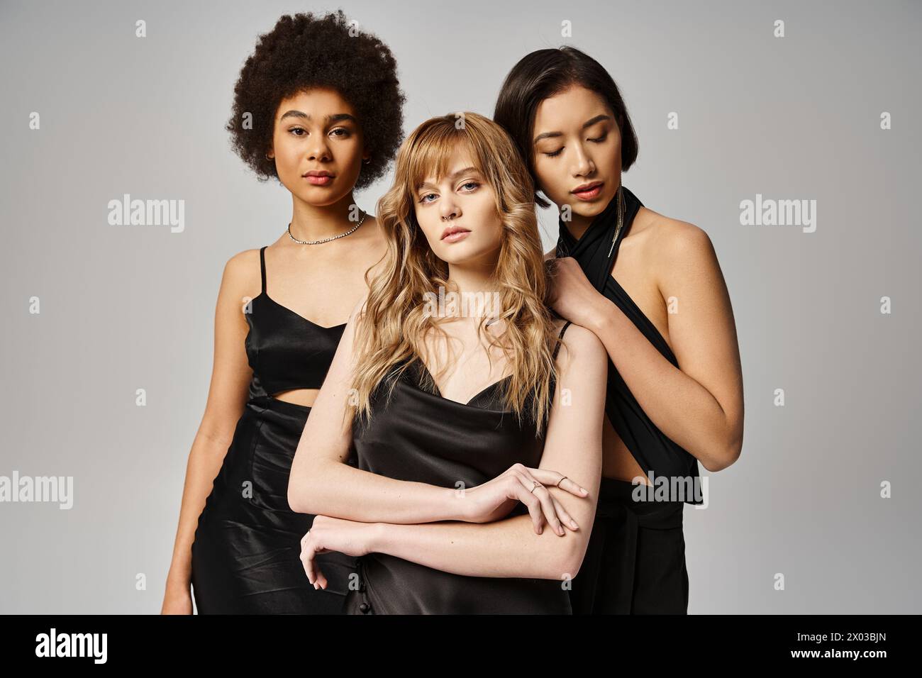 Three elegant women of different races stand gracefully together ...