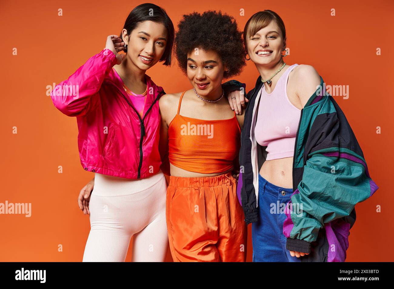 Three women of different ethnicities standing together in front of an ...
