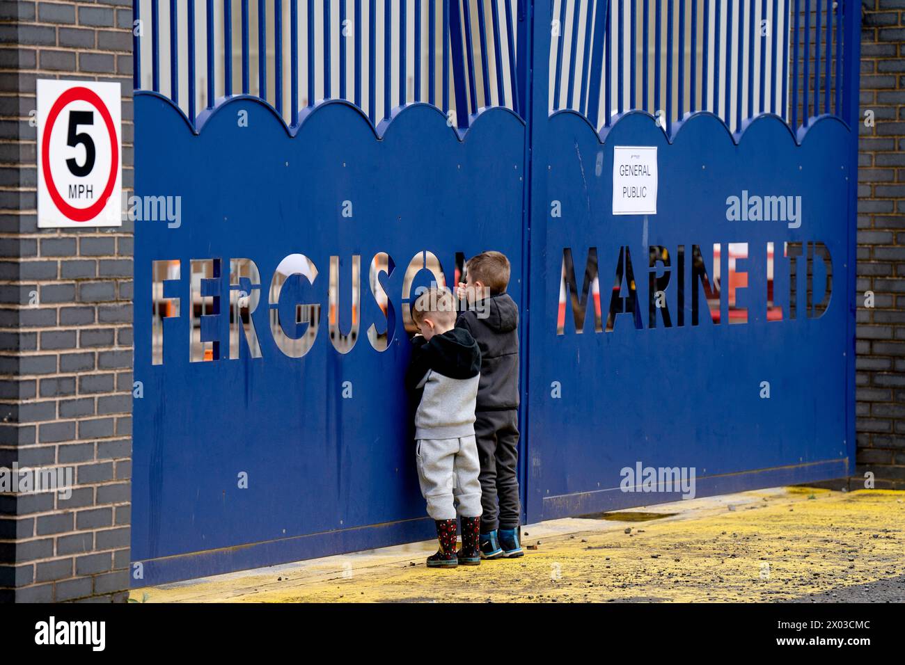 Two boys peep through the shipyard gates at the launch of the MV Glen ...