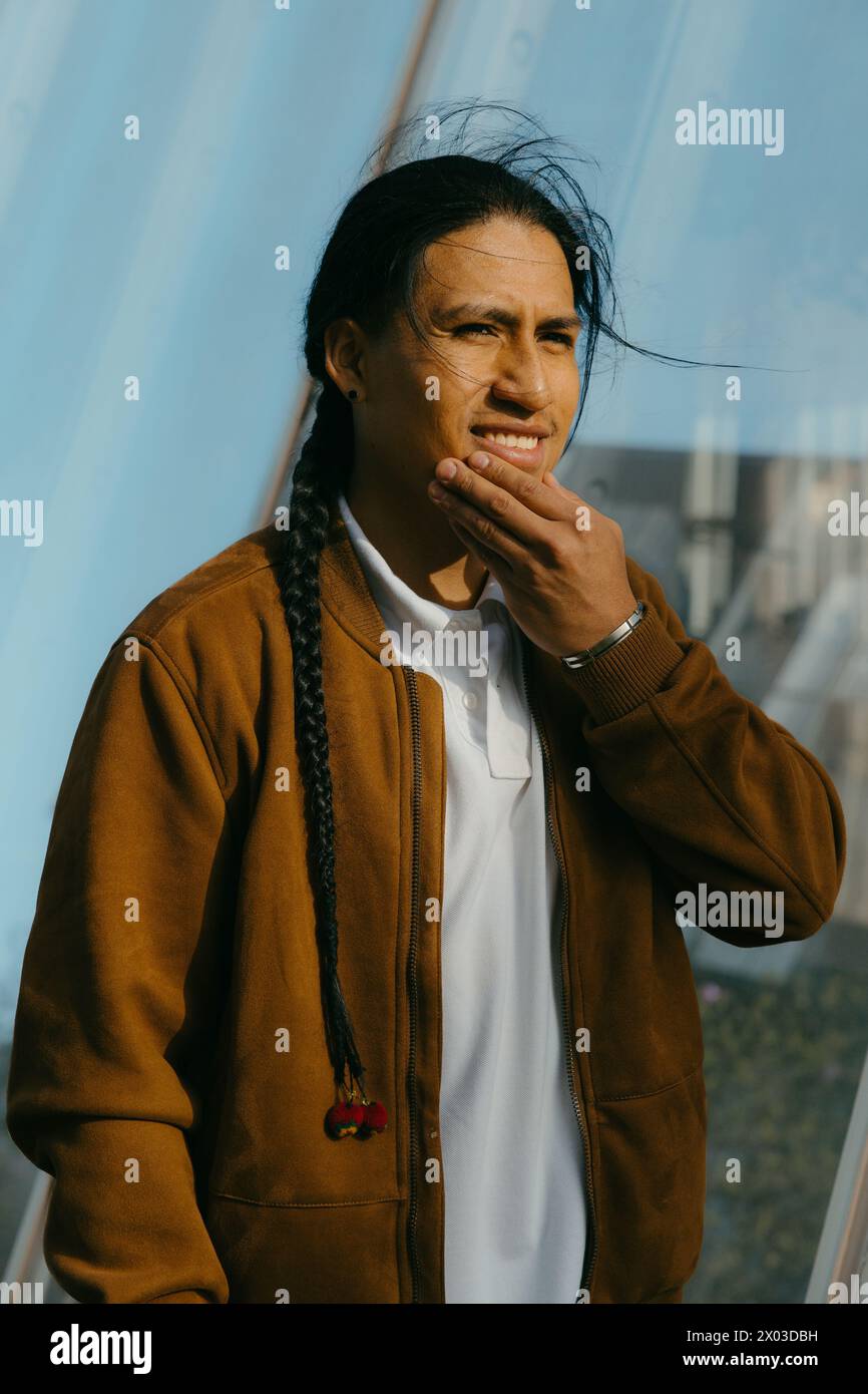 Pensive individual with a long braid touching chin, deep in thought ...