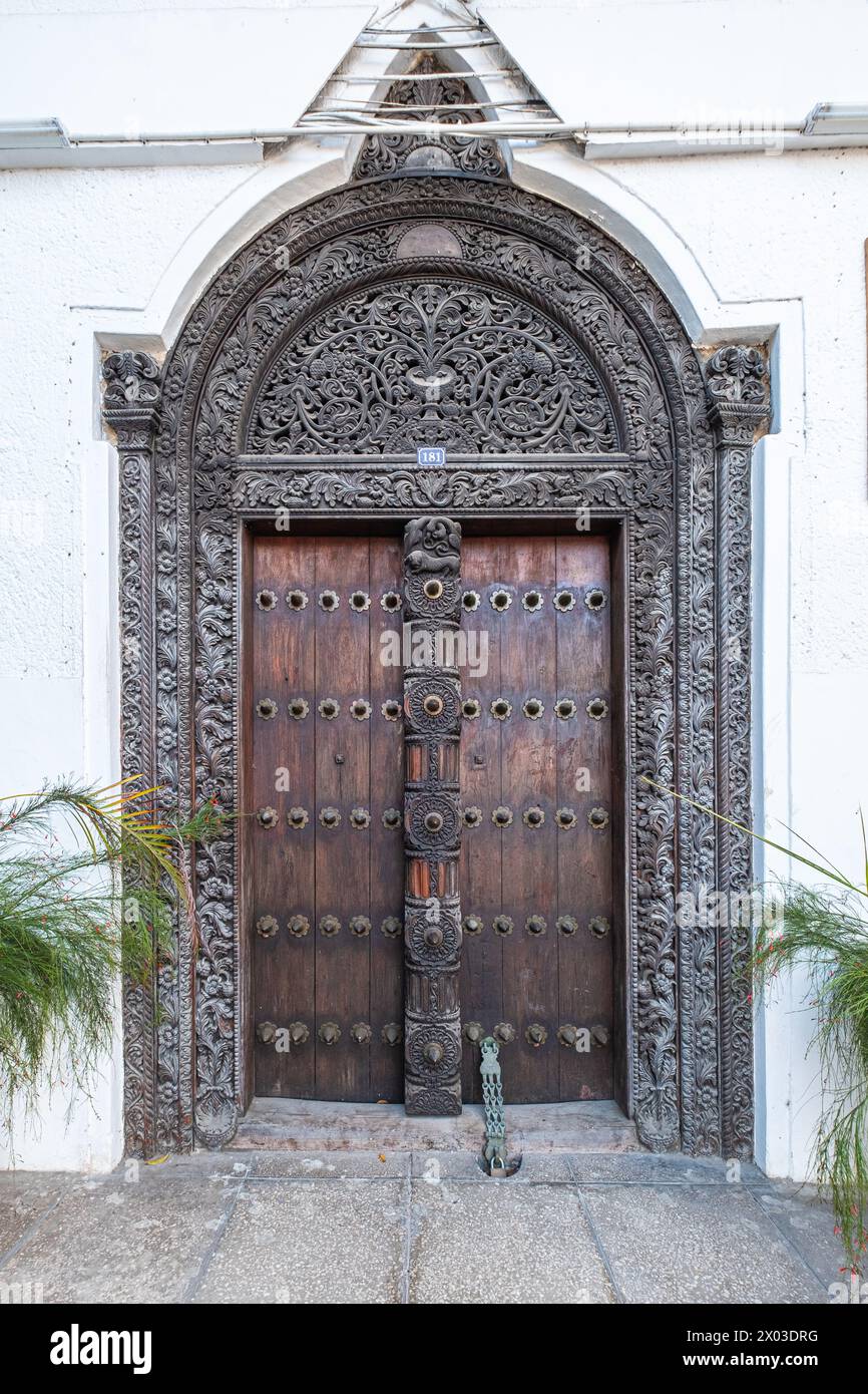 An intricately carved wooden arched door with brass doornails and an ...