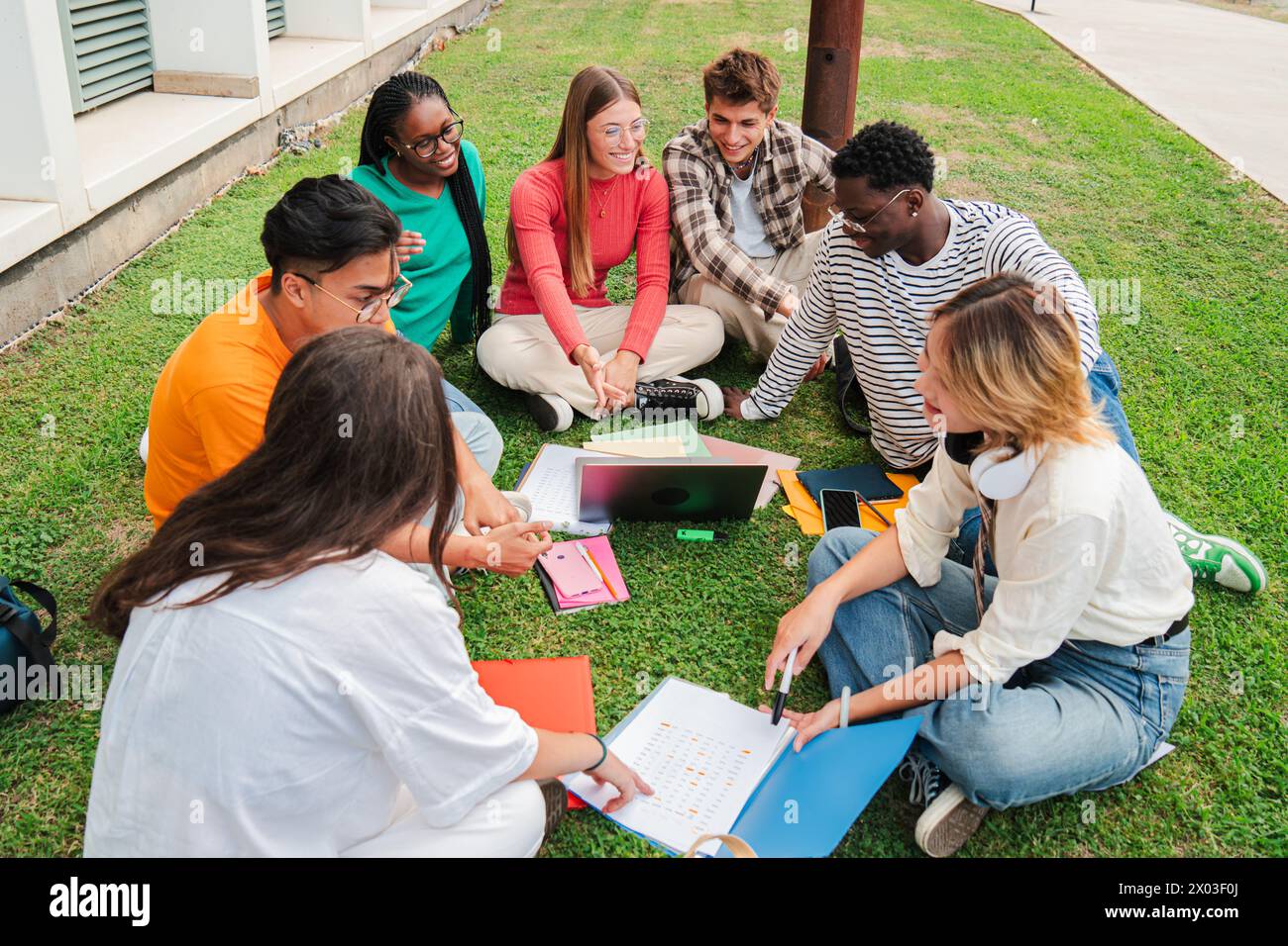Multiracial students using a laptop computert sitting in a circle on ...