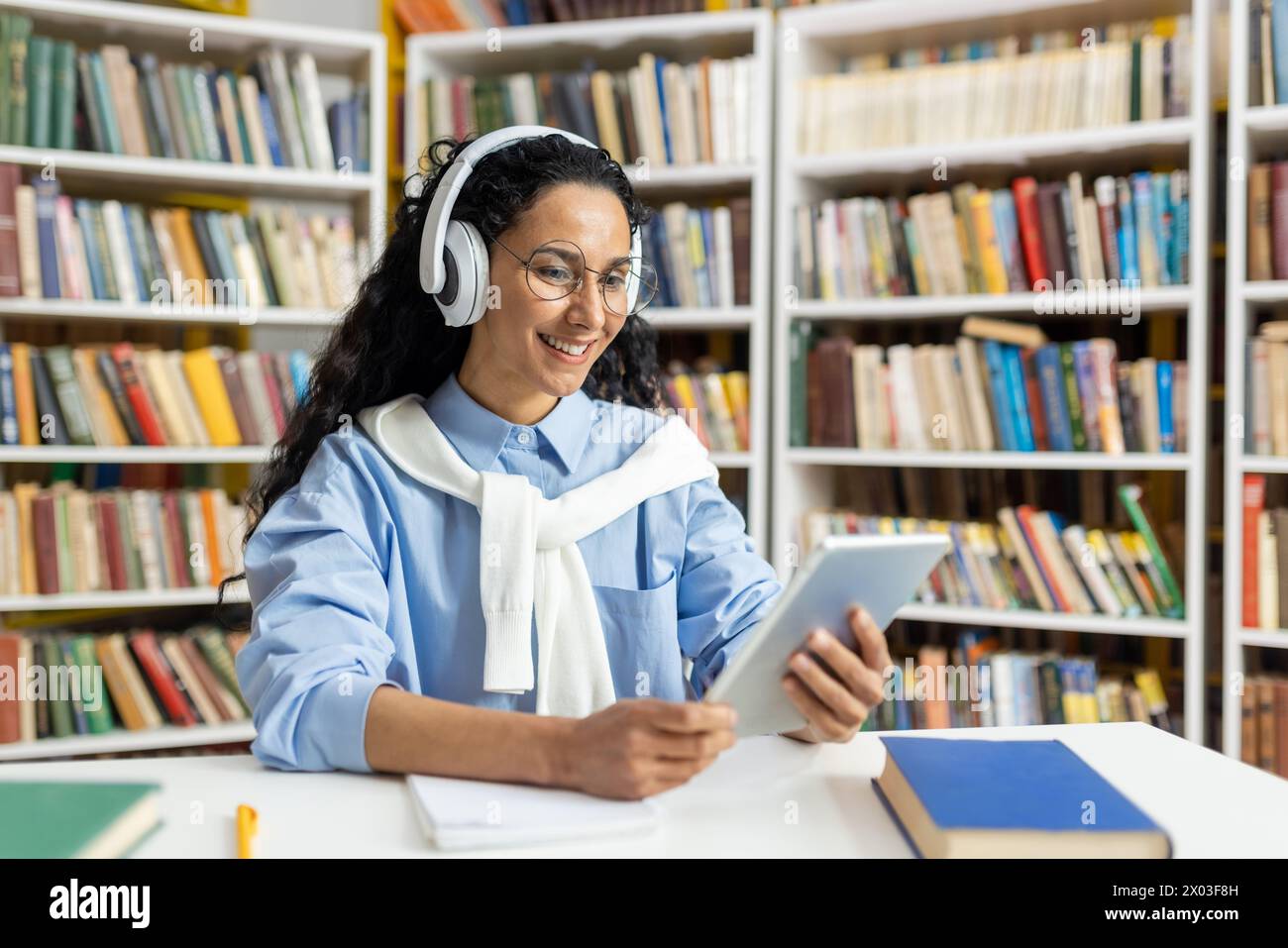 A cheerful young student engages in online learning with tablet and ...