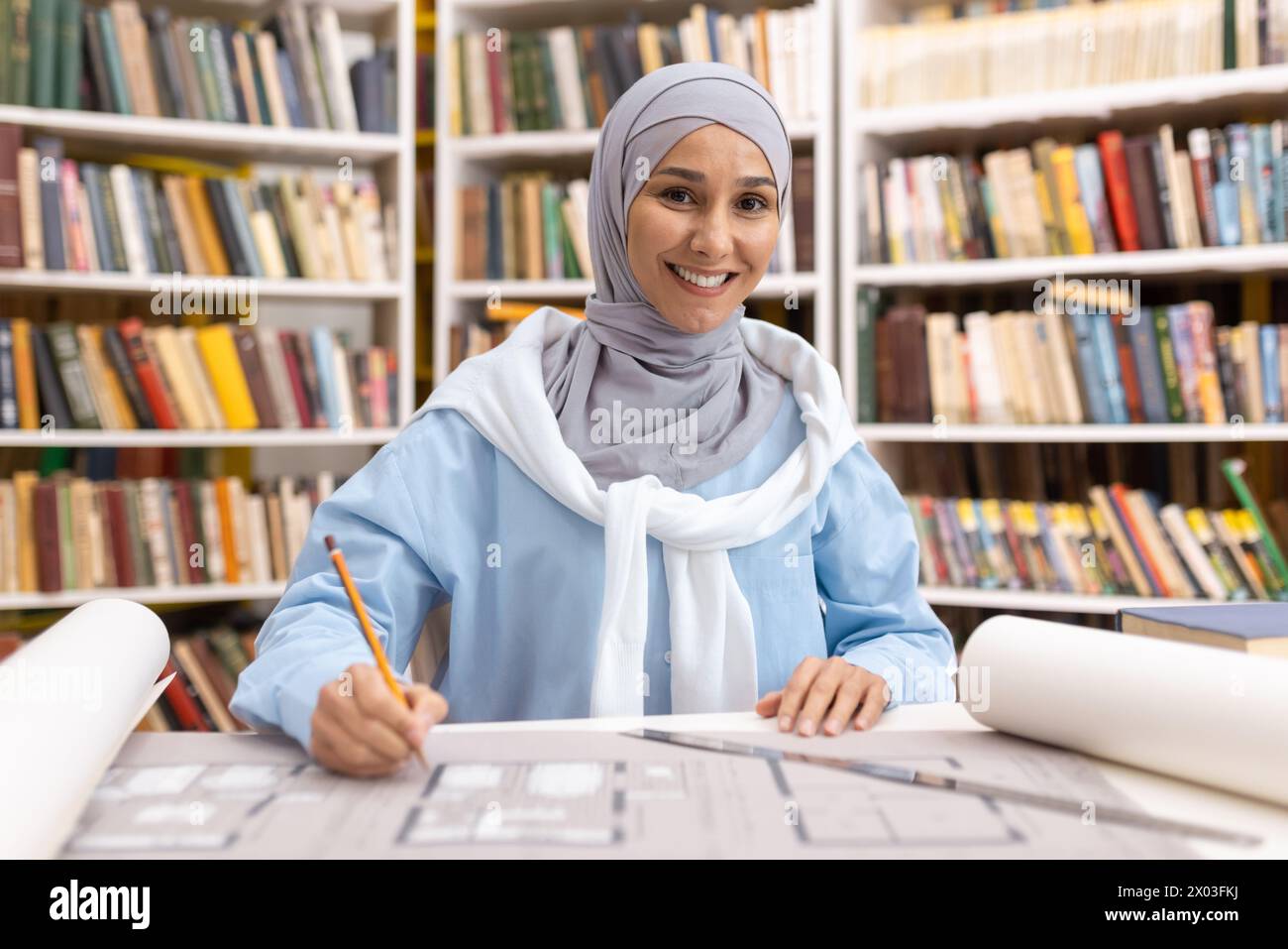 Focused Muslim architect drawing on a blueprint with pencil in a ...