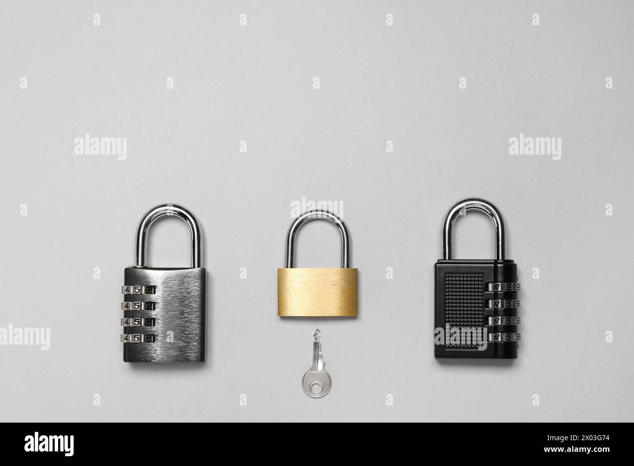 Different padlocks and key on grey background, flat lay. Space for text ...