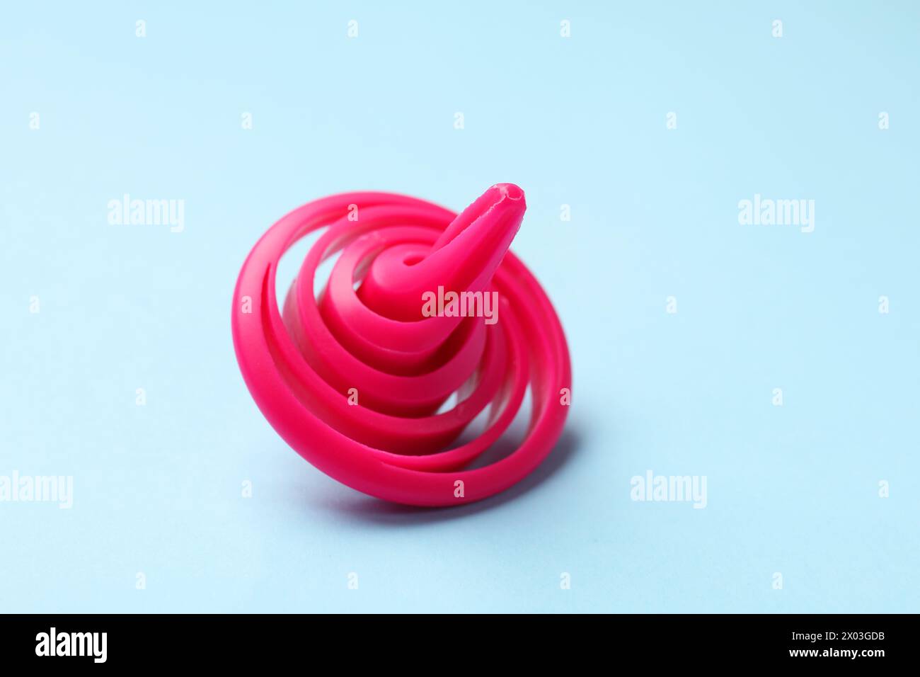 One pink spinning top on light blue background, closeup Stock Photo - Alamy