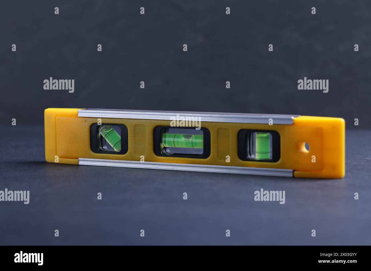 One yellow building level on dark table Stock Photo - Alamy