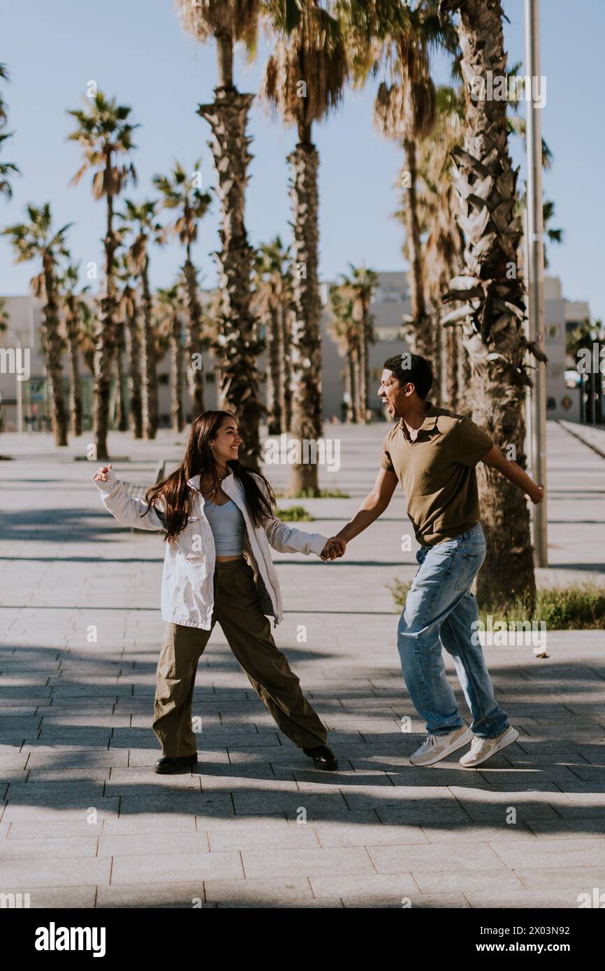 Young couple joyfully reunite on the steps of a palm-lined promenade in ...