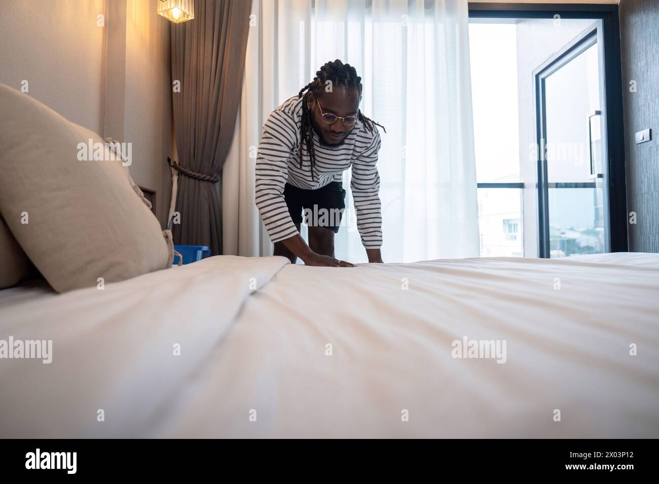 Young African American man clean making bed. happy black man changing ...