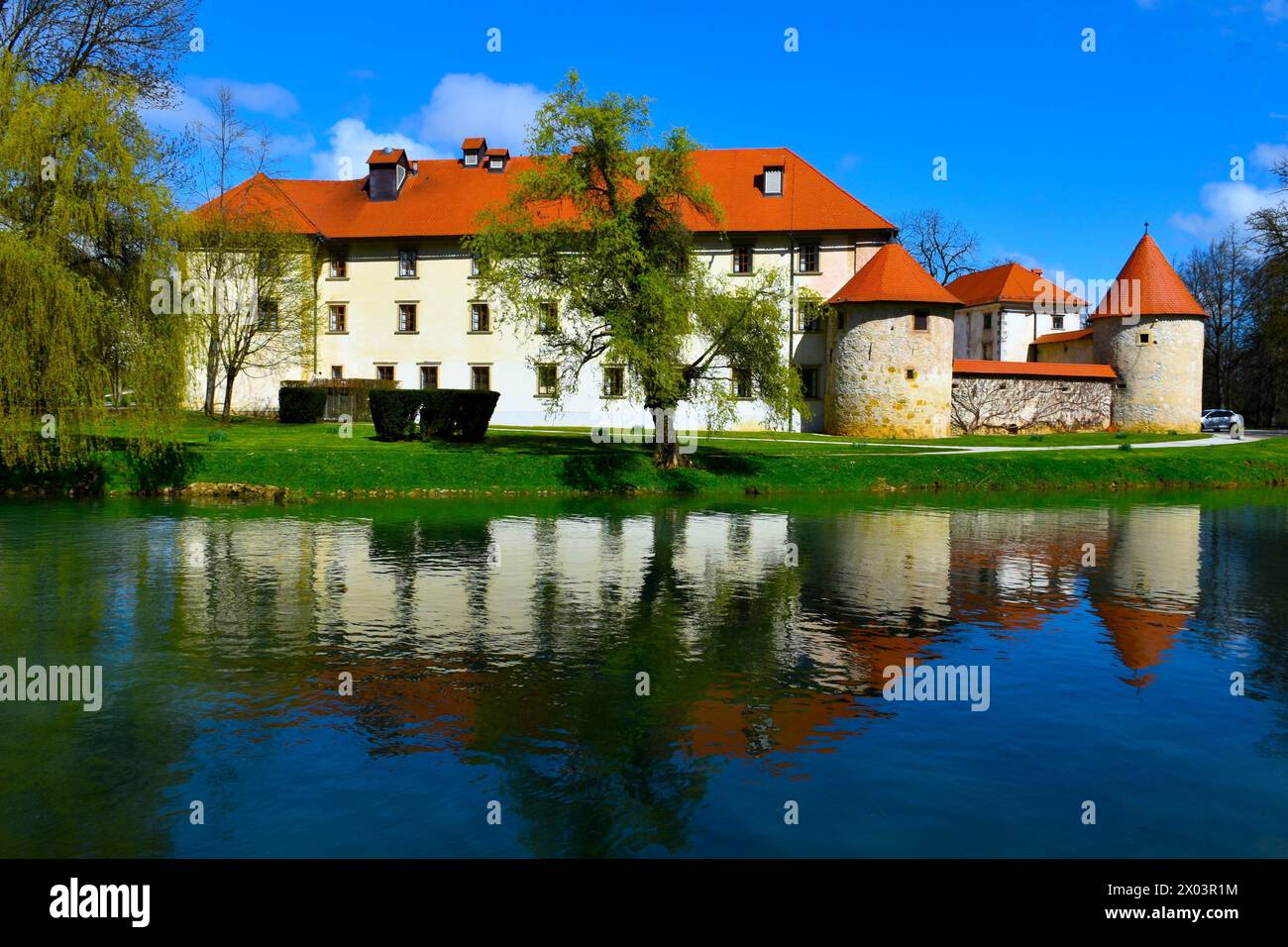 View of Otočec castle and a reflection of the castle in the water of ...