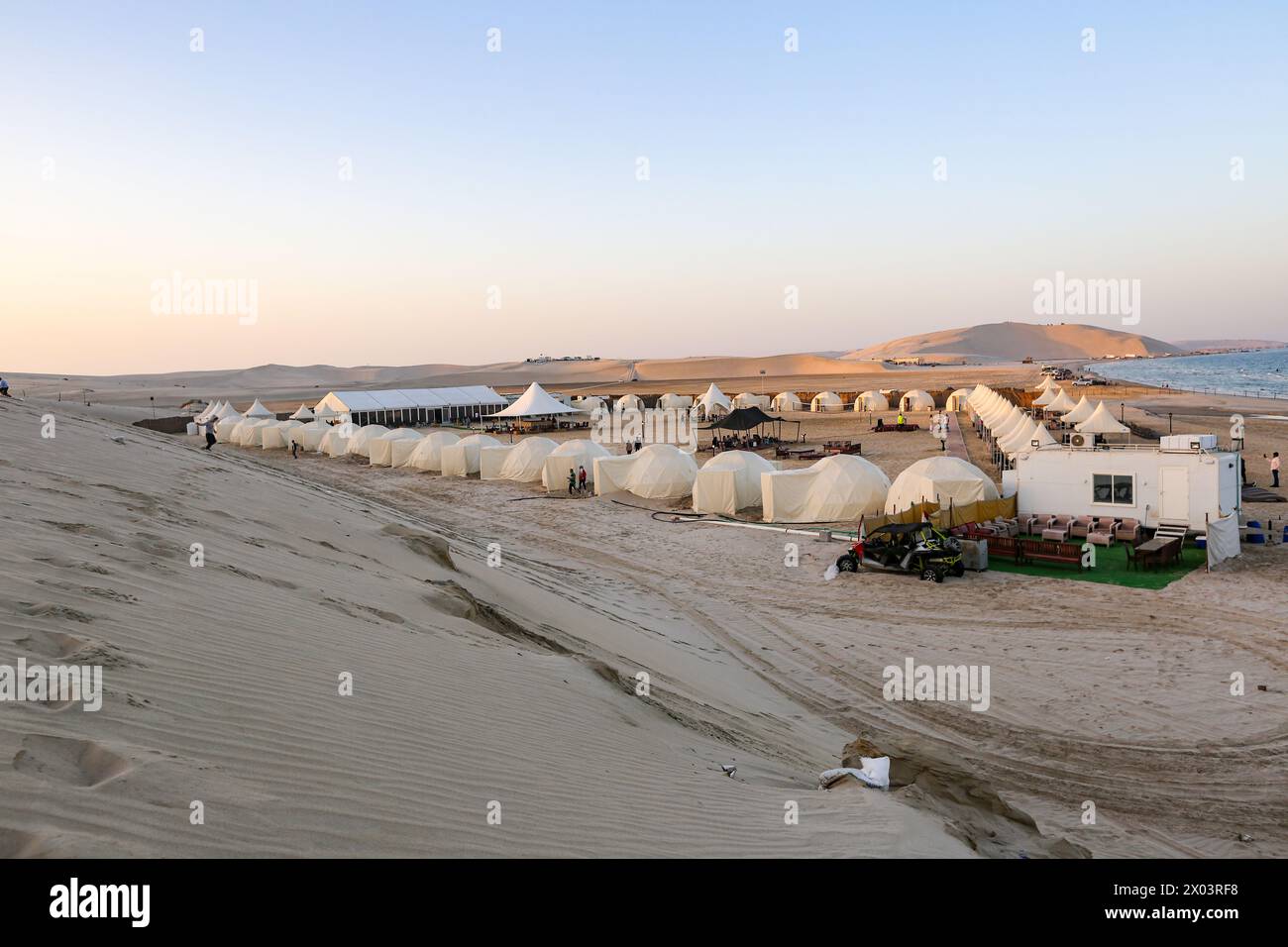 Tents at QIA desert camp at Inland Sea in Persian Gulf at sunset sky ...