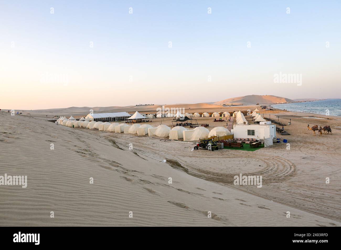 Tents at QIA desert camp at Inland Sea in Persian Gulf at sunset sky ...