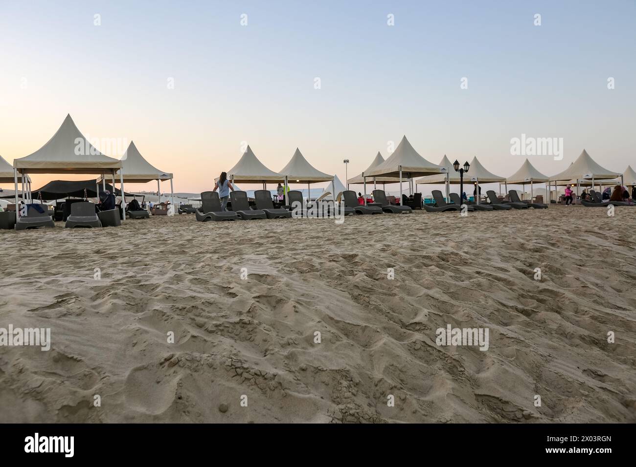 Sunbeds on the beach at sunset in sealine, inland sea, a top tourist ...