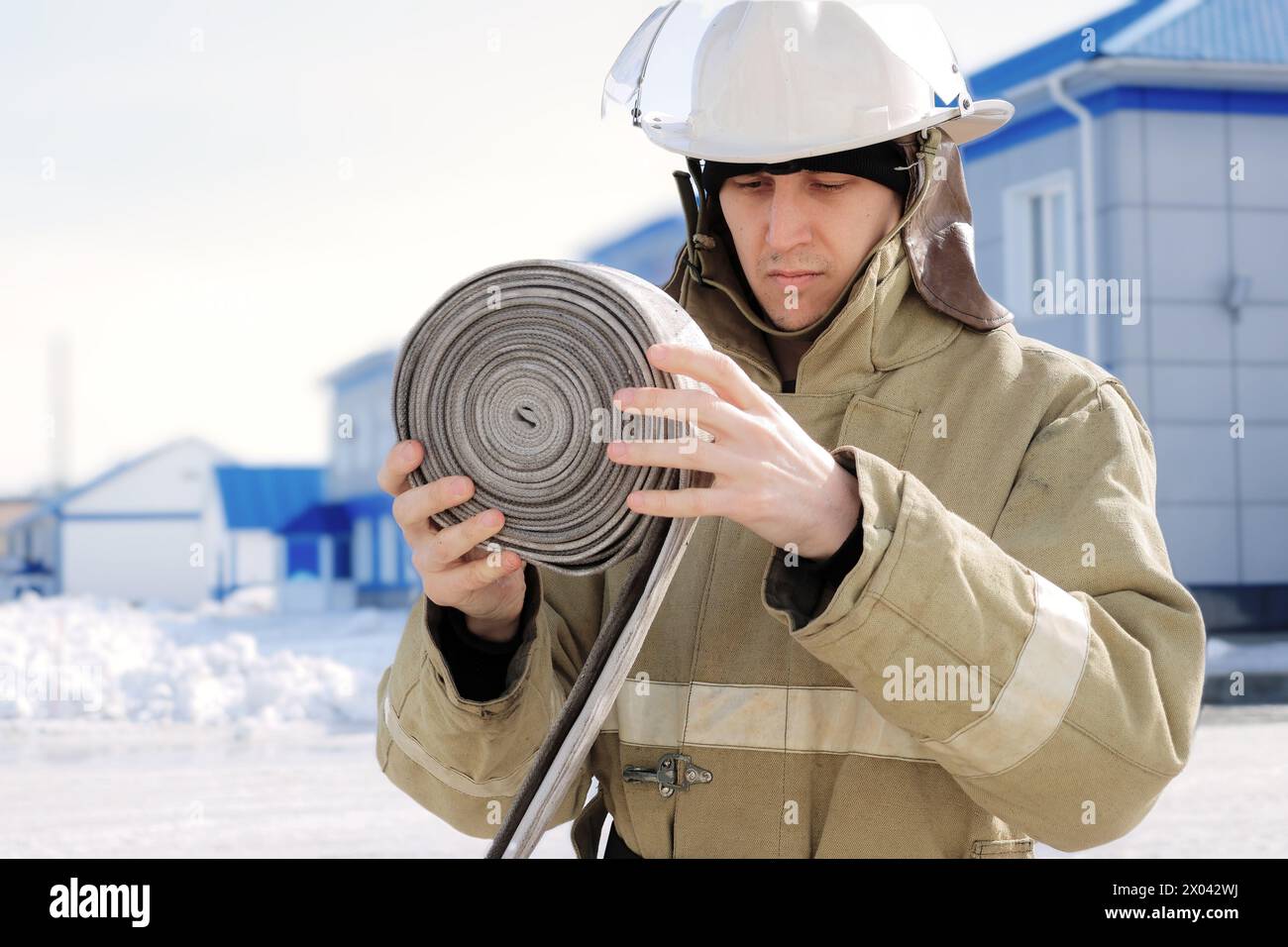 A firefighter in full gear carefully inspects a rolled fire hose during ...