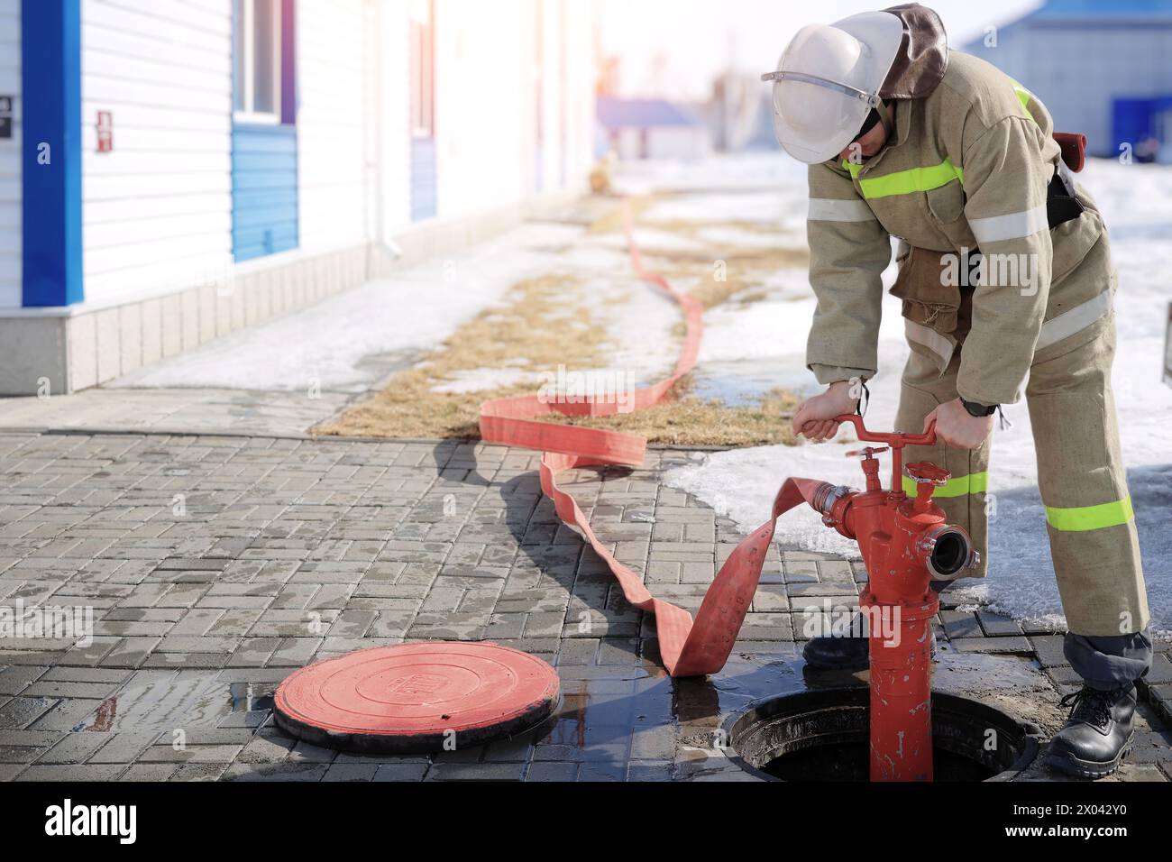 Image of a firefighter connecting a red fire hose to a hydrant for ...