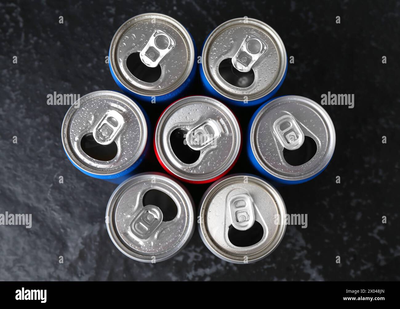 Energy drinks in wet cans on black textured table, flat lay. Functional ...