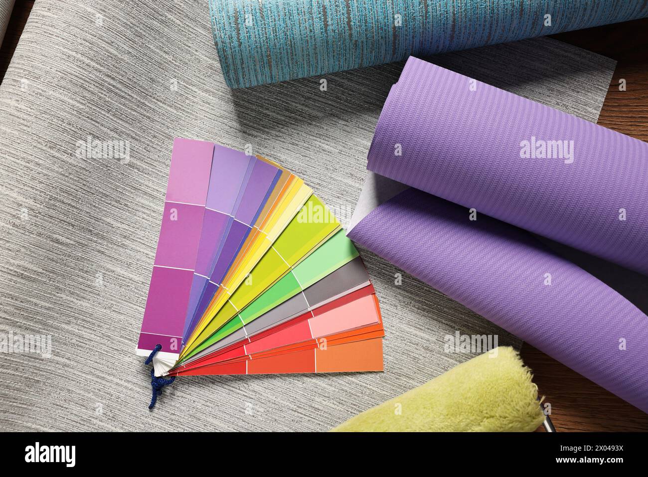 Different wallpaper rolls, roller and color palette samples on table ...