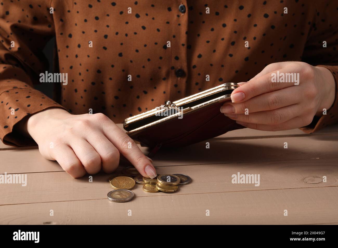 Poverty. Woman with wallet counting coins at wooden table, closeup ...