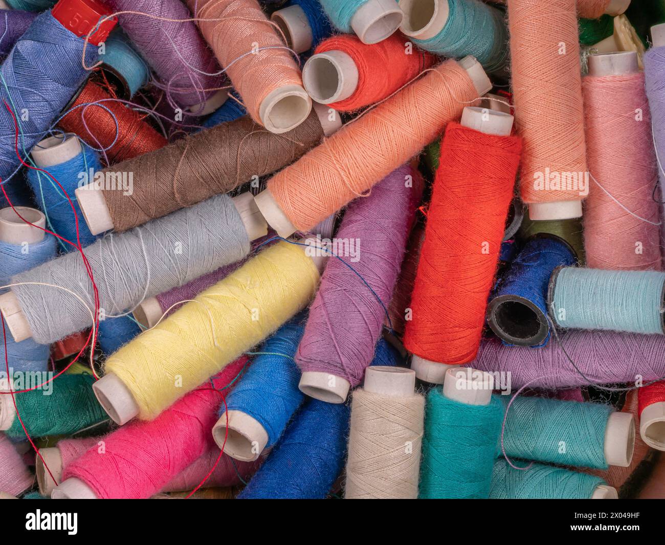 Many colorful threads on spools in disarray Stock Photo - Alamy