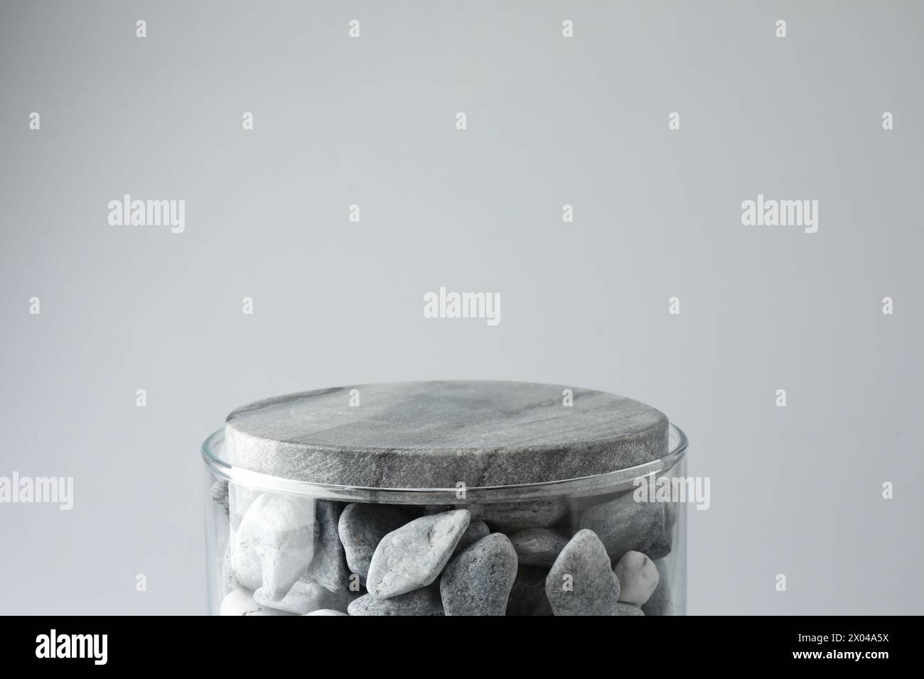 Presentation for product. Glass container with stones on light grey ...