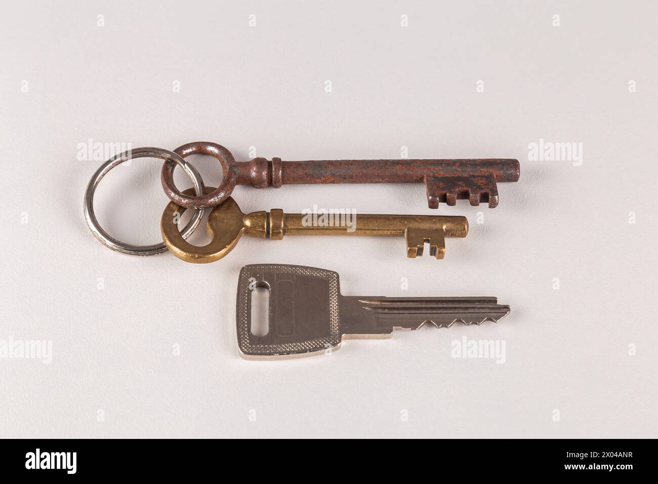 Two old and one new keys on a white surface Stock Photo - Alamy