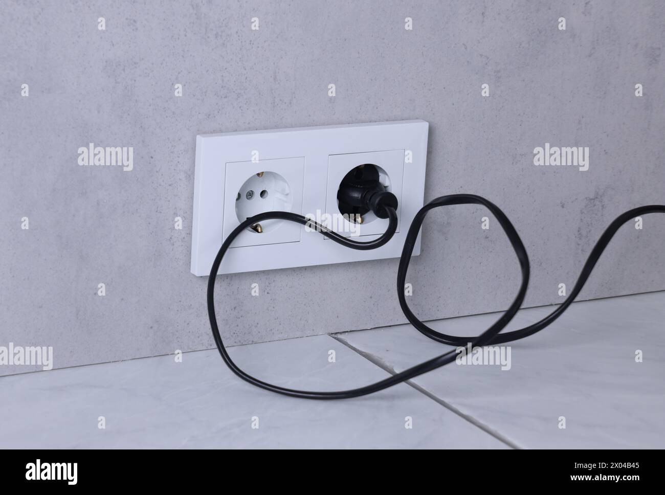Power sockets and electric plug on grey wall Stock Photo - Alamy