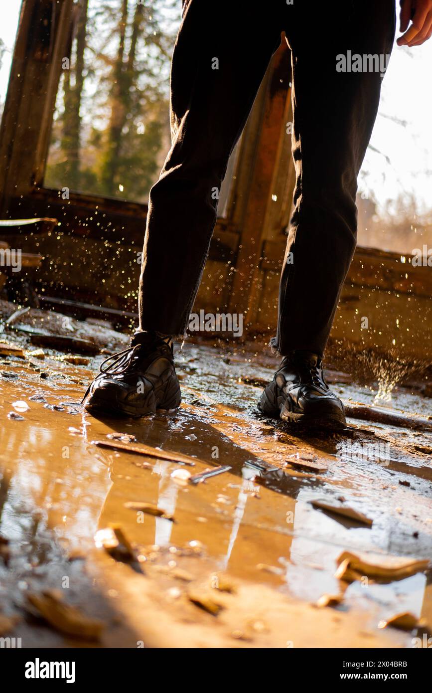 Male legs in black pants and sneakers among the puddle and frozen drops ...