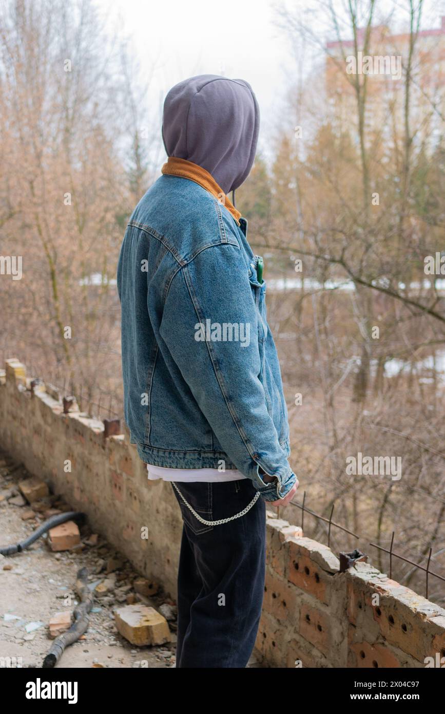 A handsome guy in a denim jacket and a gray hood poses against the ...